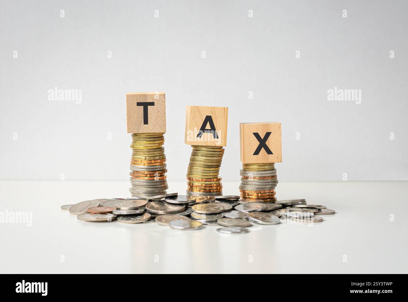 Tax word on wooden blocks, on top of coins, stacked and lying on table ...