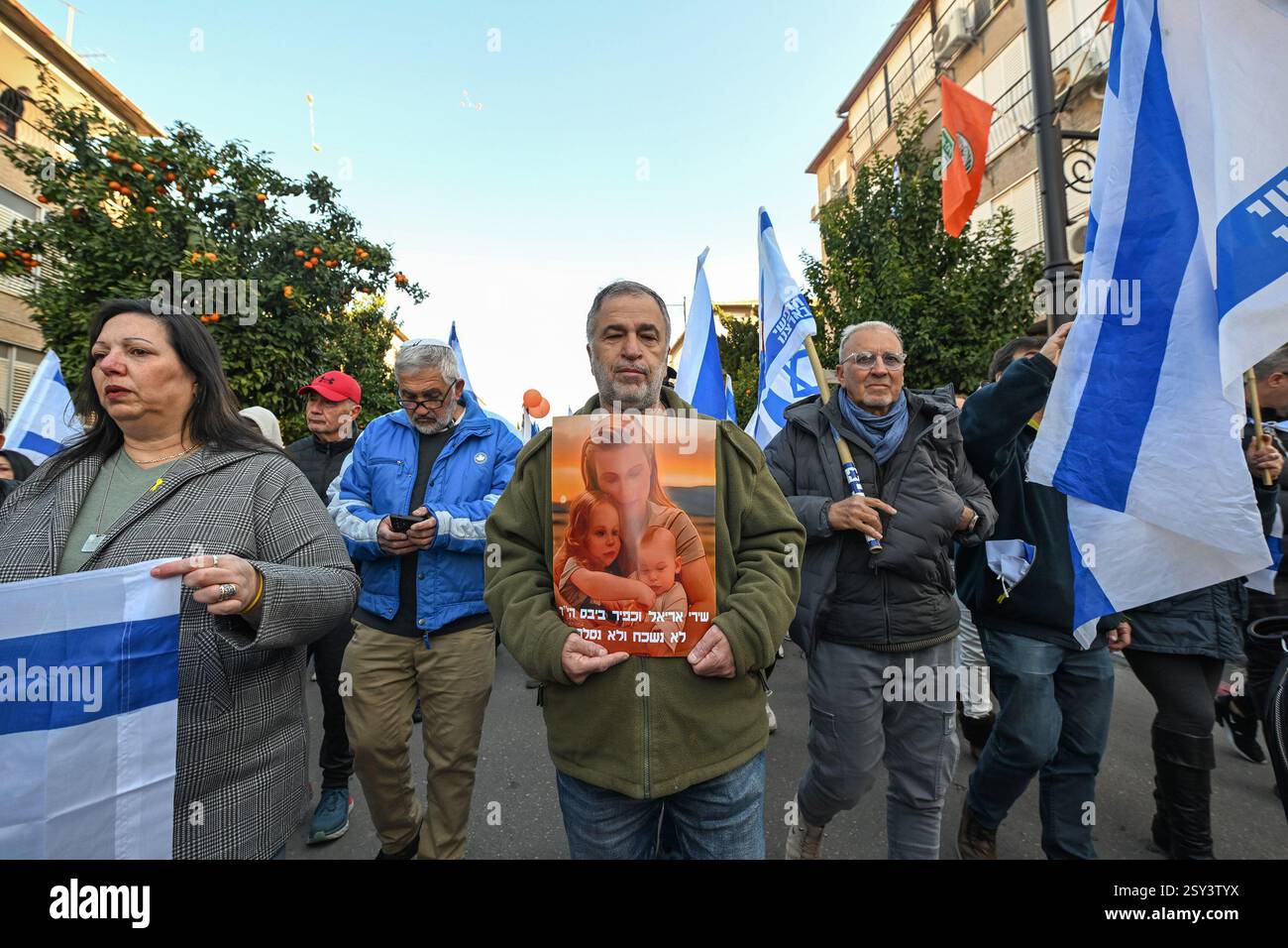 A man with a picture of Shiri Biabs and her children walks in the crowd ...