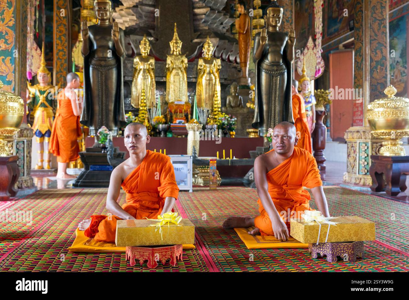 Two monks dressed in orange robes perform a water blessing ceremony at ...