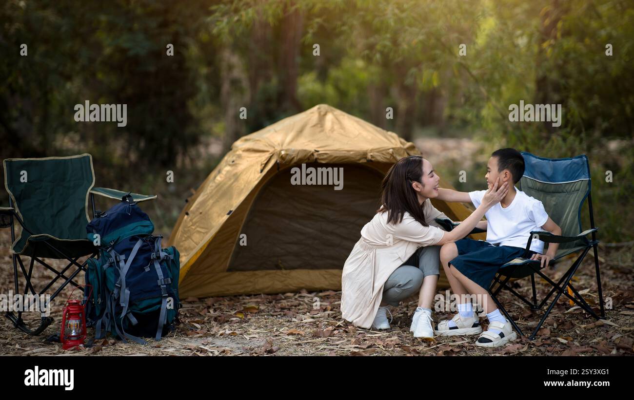The smiling mother is touching her son face in front of the camping ...