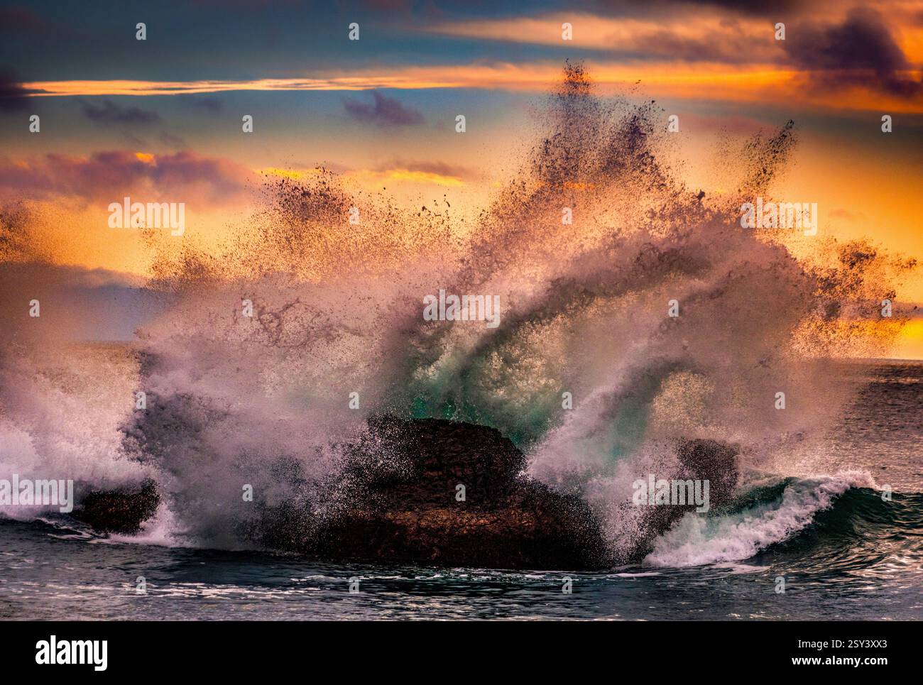 Powerful wave crashes against a coastal rock causing a huge splash into ...