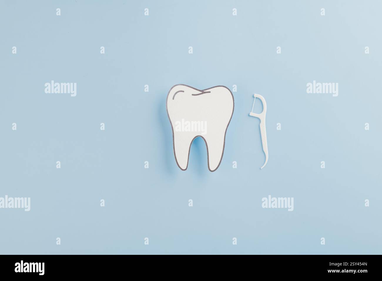 Dentist Day concept. A paper tooth model and floss on a blue background ...