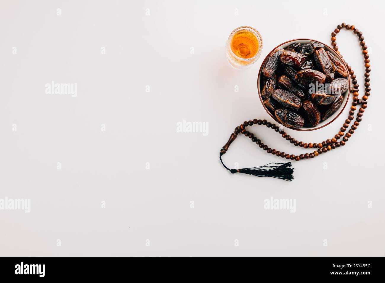 Dates, tea, and beads arranged for Ramadan Kareem on a white flat lay ...
