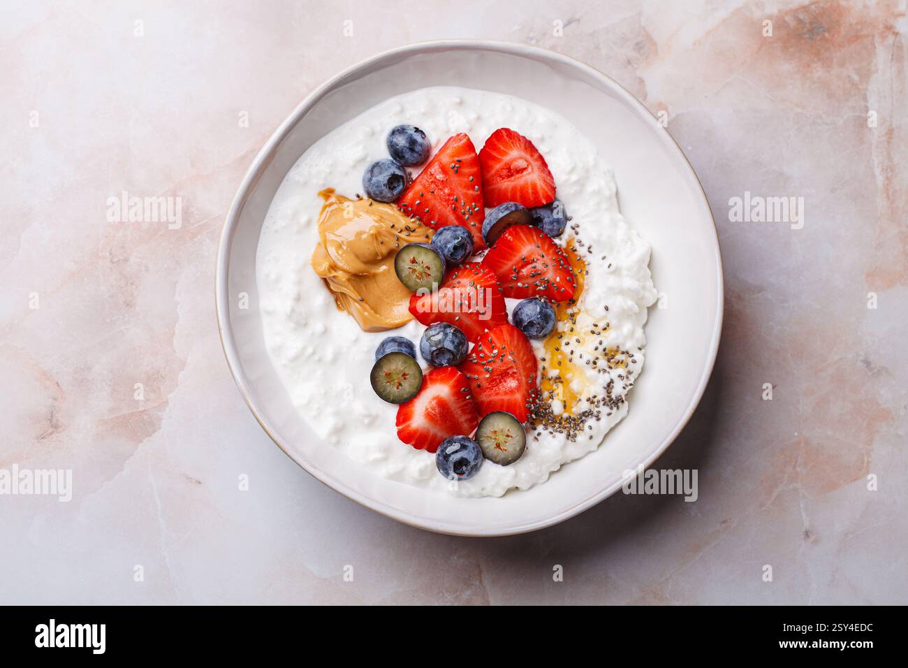 Cottage cheese with berries, peanut butter and honey, top view. Healthy ...
