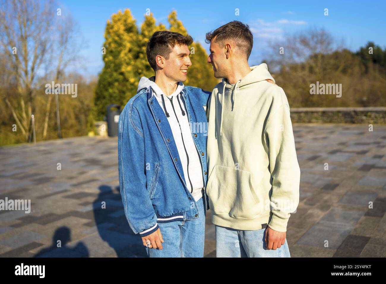 Two men embracing and smiling in a public park, sharing a joyful ...