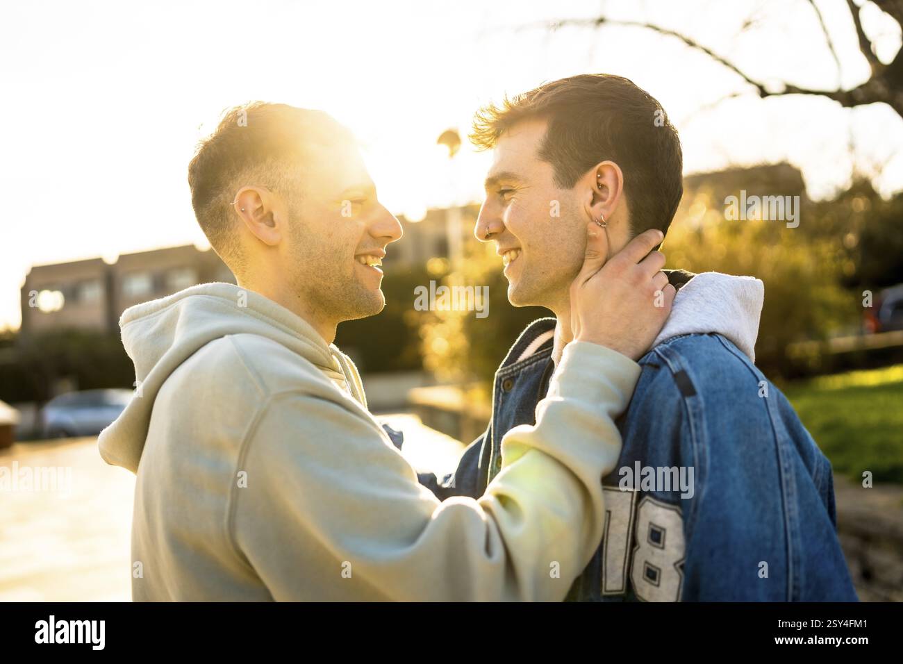 Two men are embracing and smiling at each other in the golden light of ...