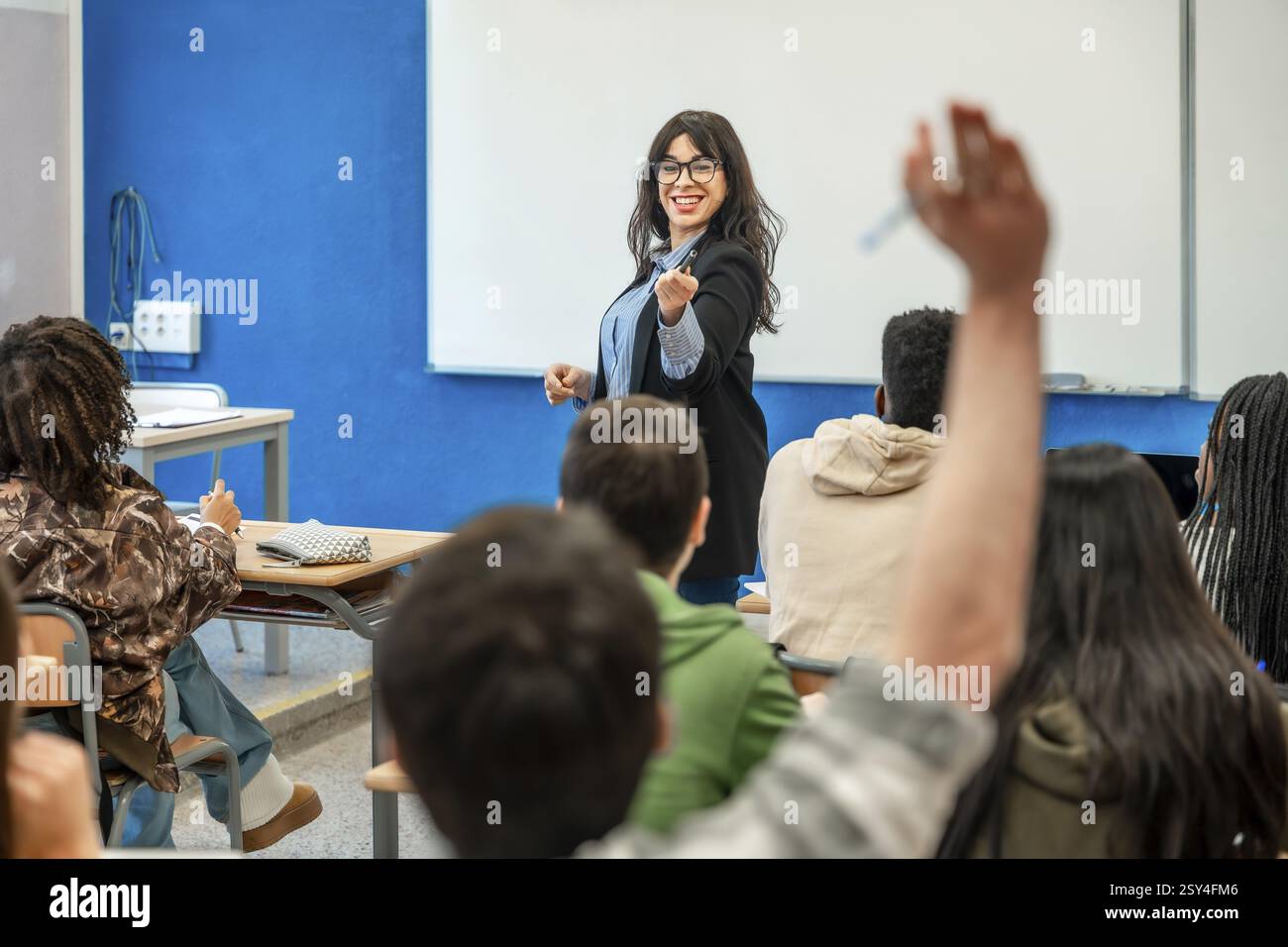 University professor pointing at a student raising hand to answer a ...