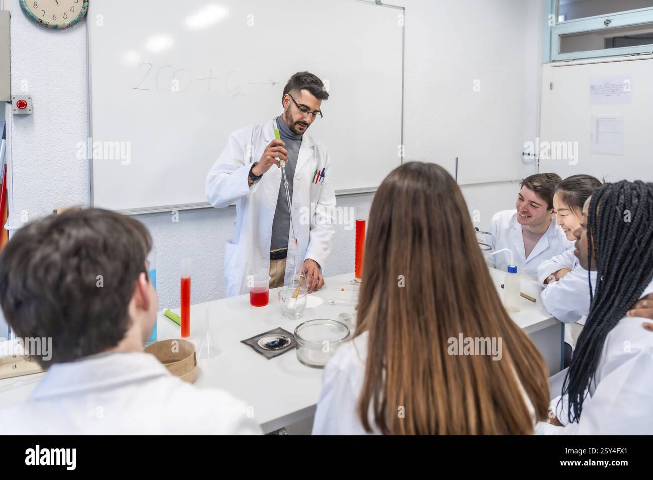 Chemistry teacher performing a chemical experiment with students in a ...