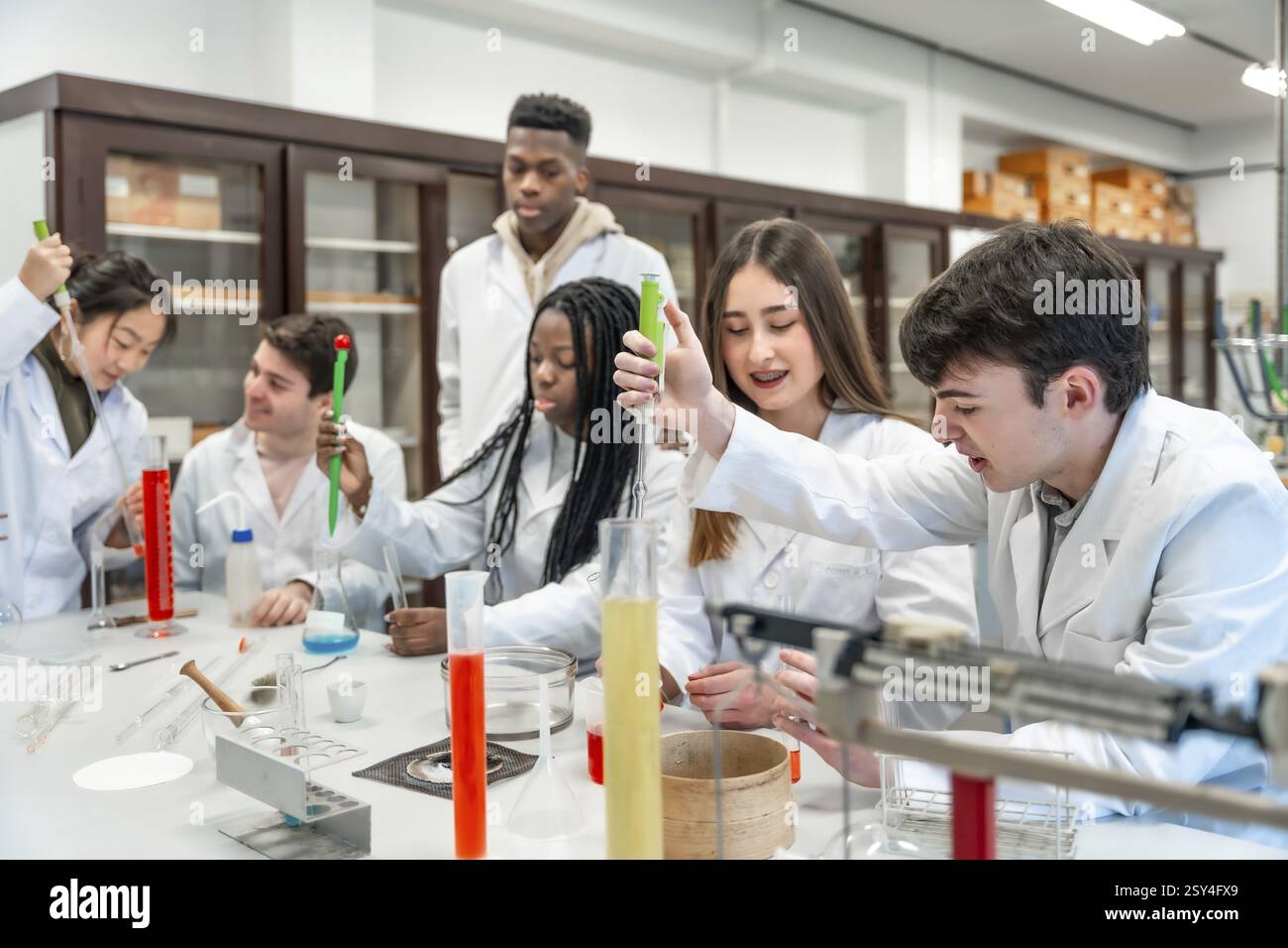Multi ethnic university students wearing lab coats conducting a ...