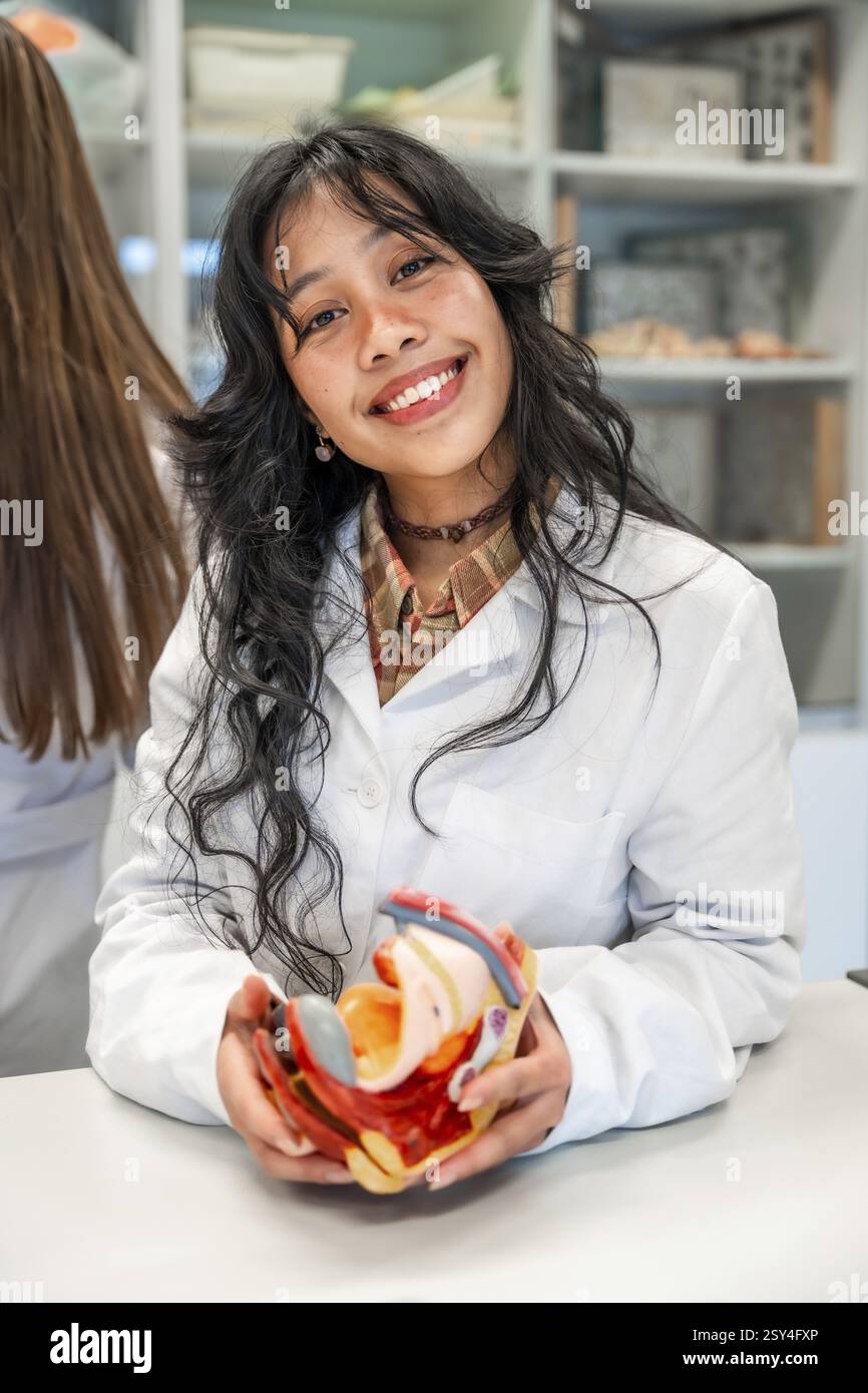 Smiling medical student holding anatomical model of female reproductive ...