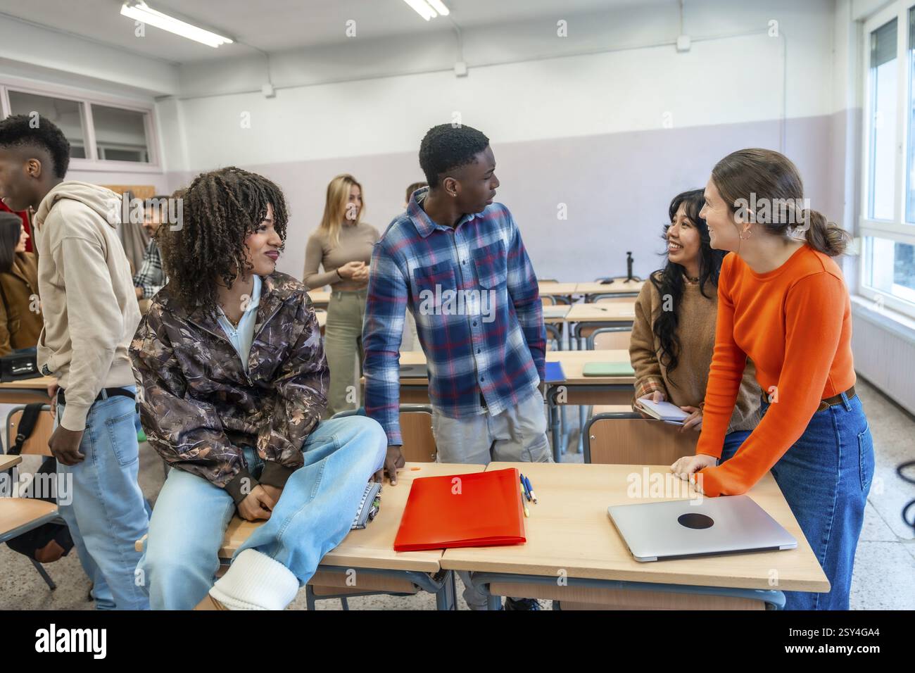 Multi ethnic university students engaging in lively conversation after class, creating ...