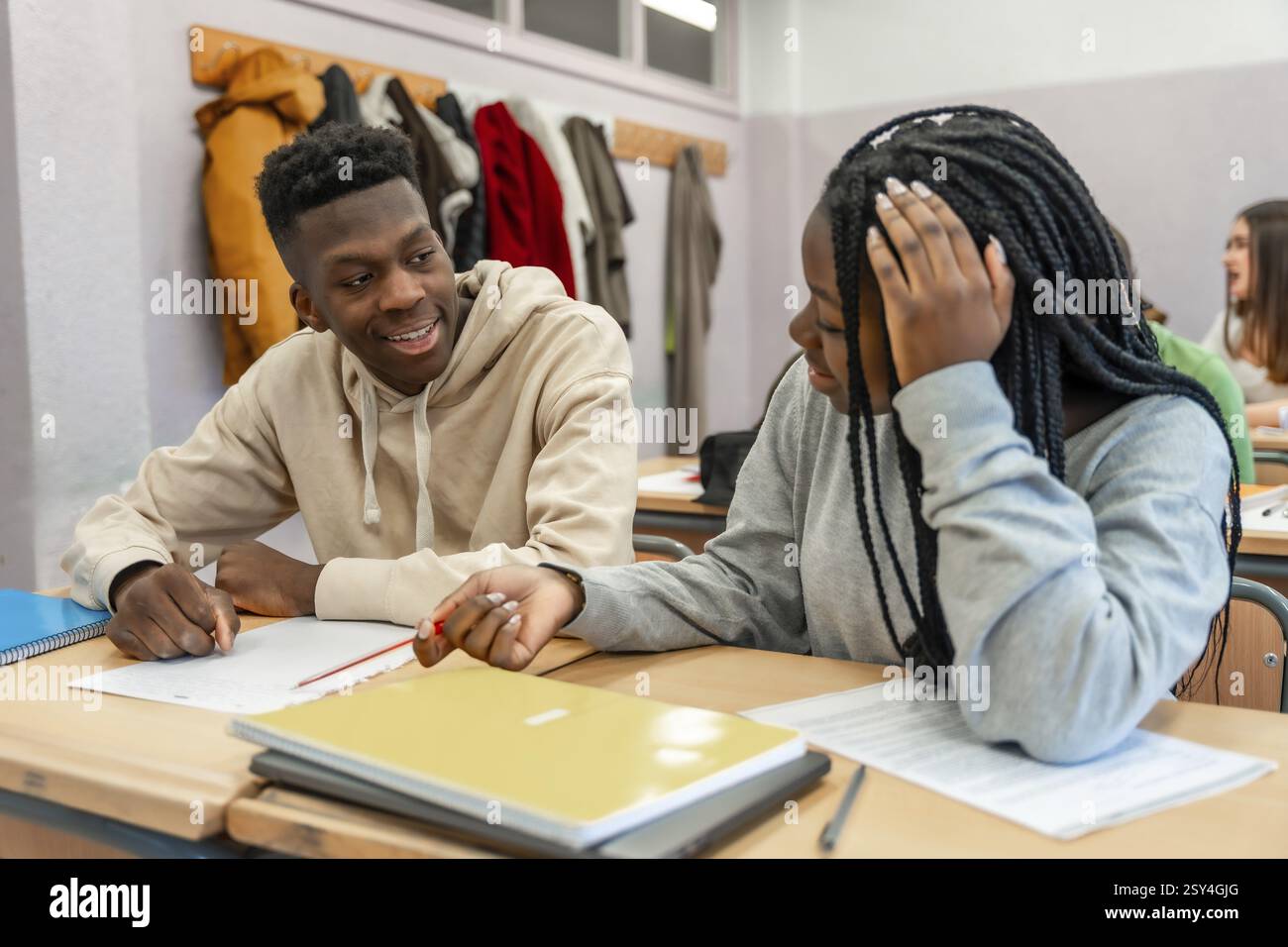 Two high school students working together on a project, sharing ideas and collaborating in a ...