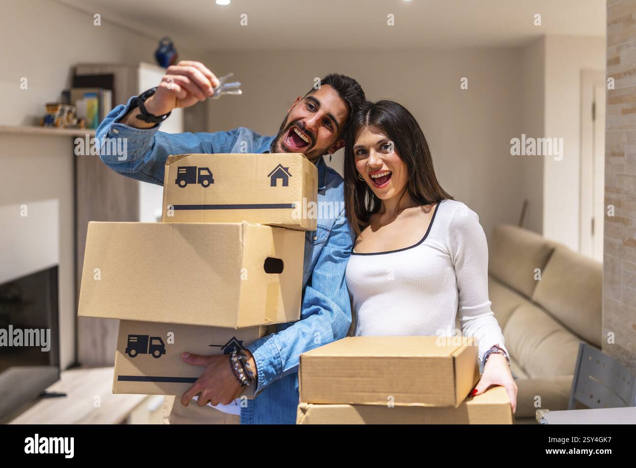 Excited couple showing house keys while carrying cardboard boxes ...