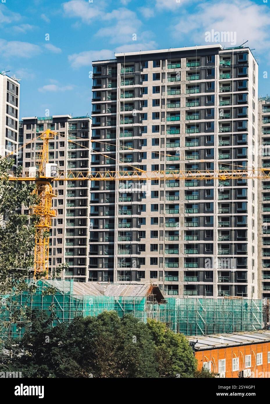 A tall yellow construction crane stands between modern high-rise ...