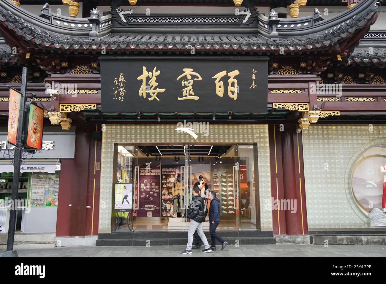 Tourists walk past the flagship store of Anta in Shanghai, China ...