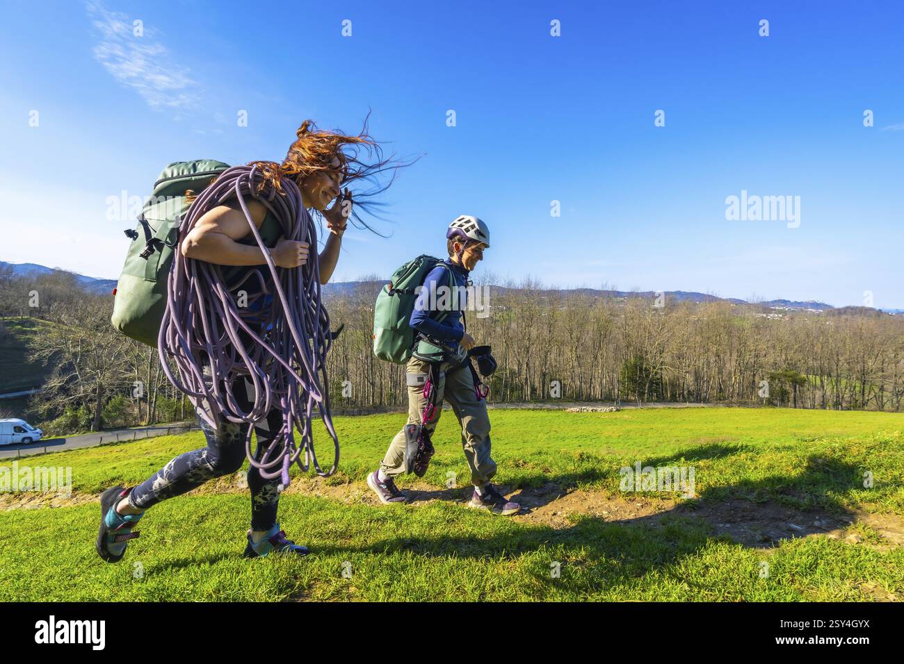 Two women climbers are walking on a meadow carrying climbing ropes and ...