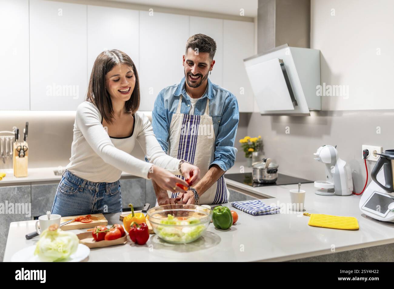 Young couple smiling and joyfully preparing a vibrant, healthy salad ...