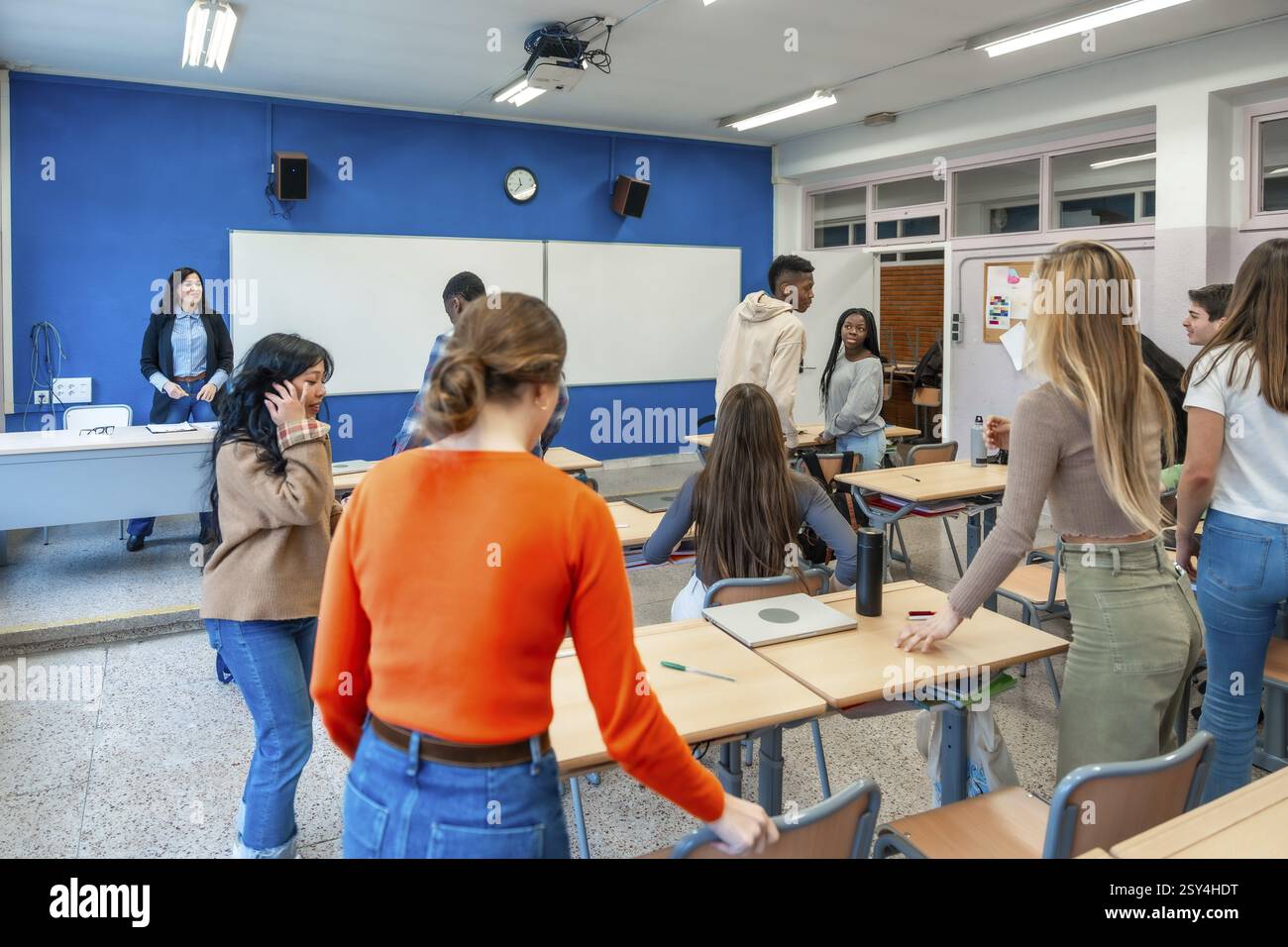 Multi ethnic group of high school students leaving classroom after ...