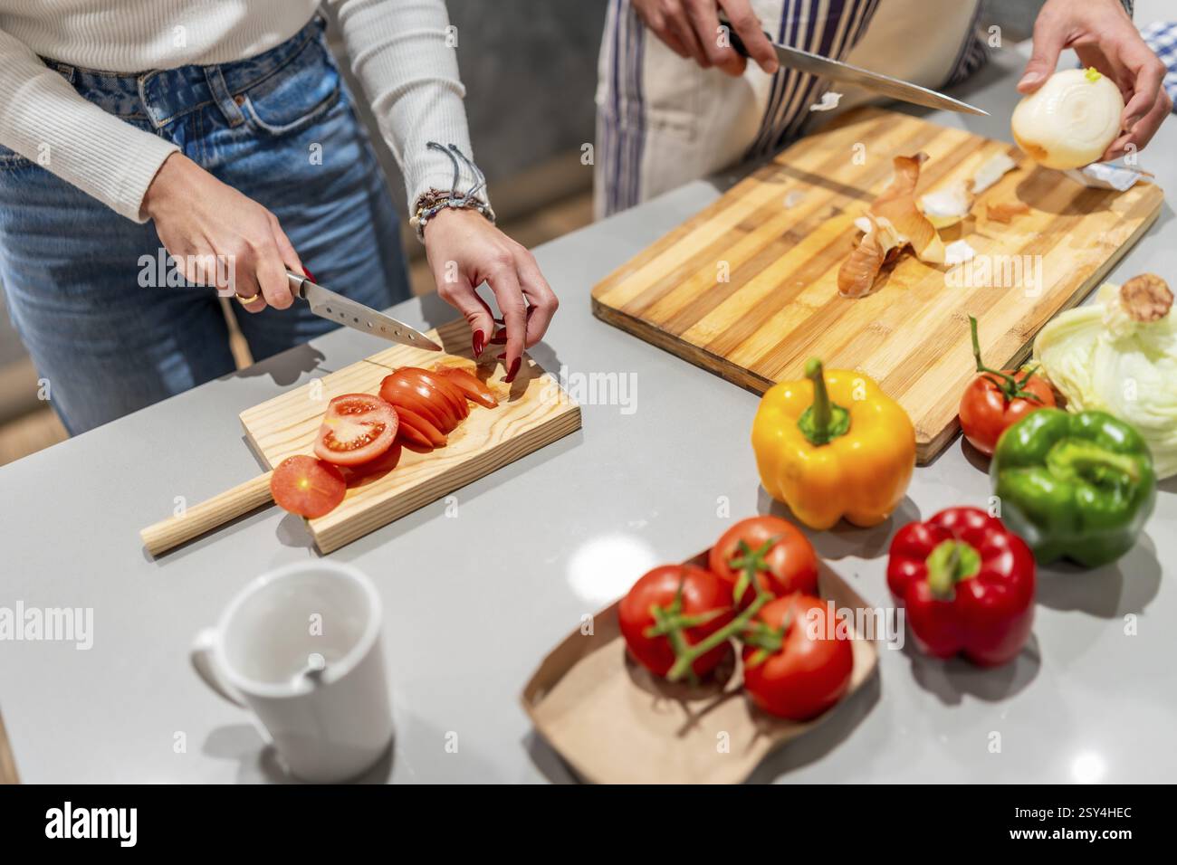 Two chefs slicing fresh tomatoes and onions on wooden cutting boards ...