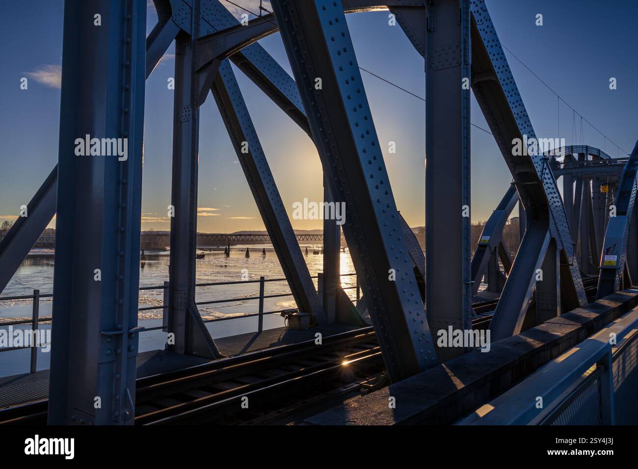 Framed by steel and sky, the frozen river flows beneath, sculpting ice ...