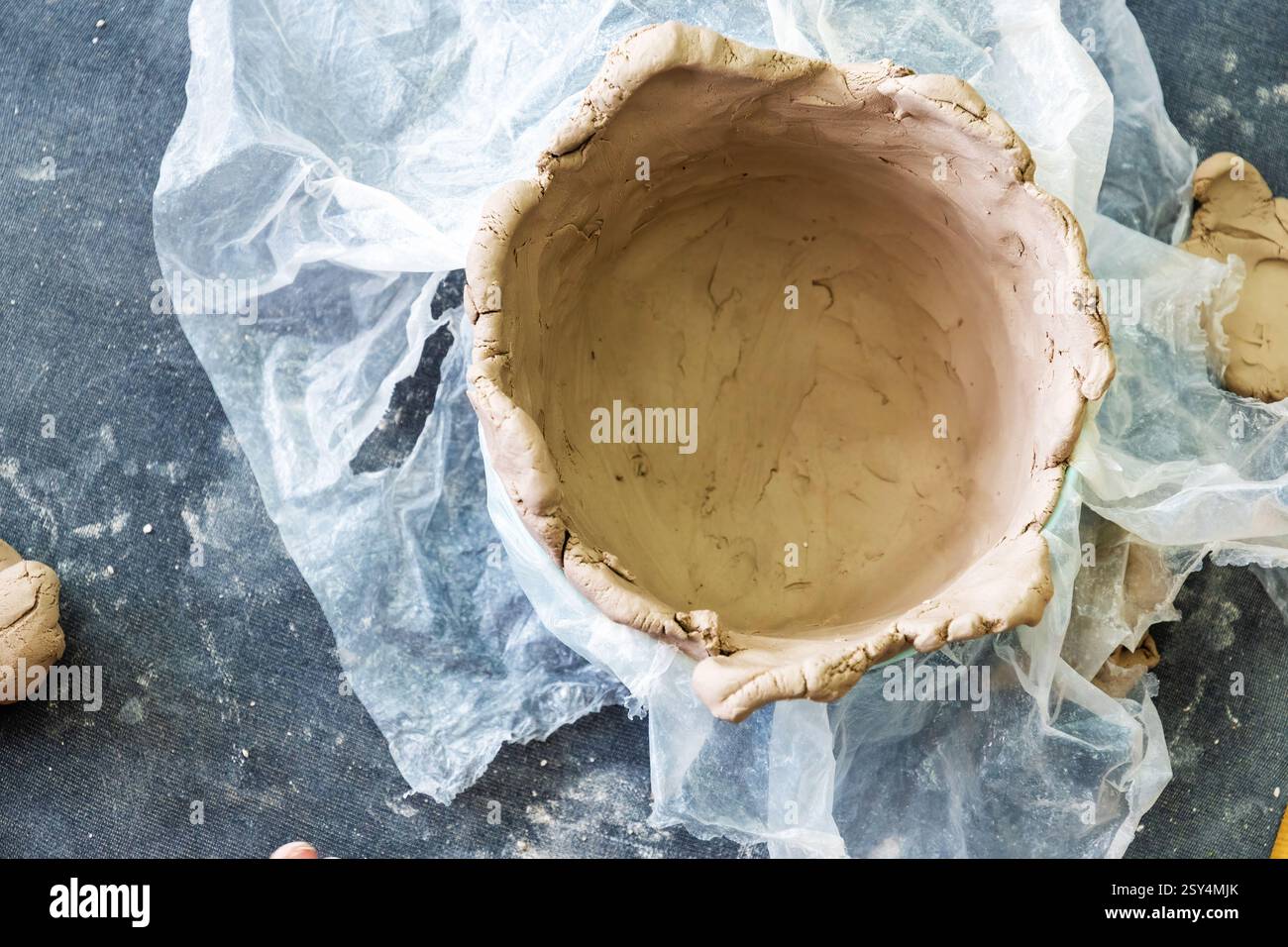 A close-up shot of an unfinished clay bowl, still wet and showing the ...