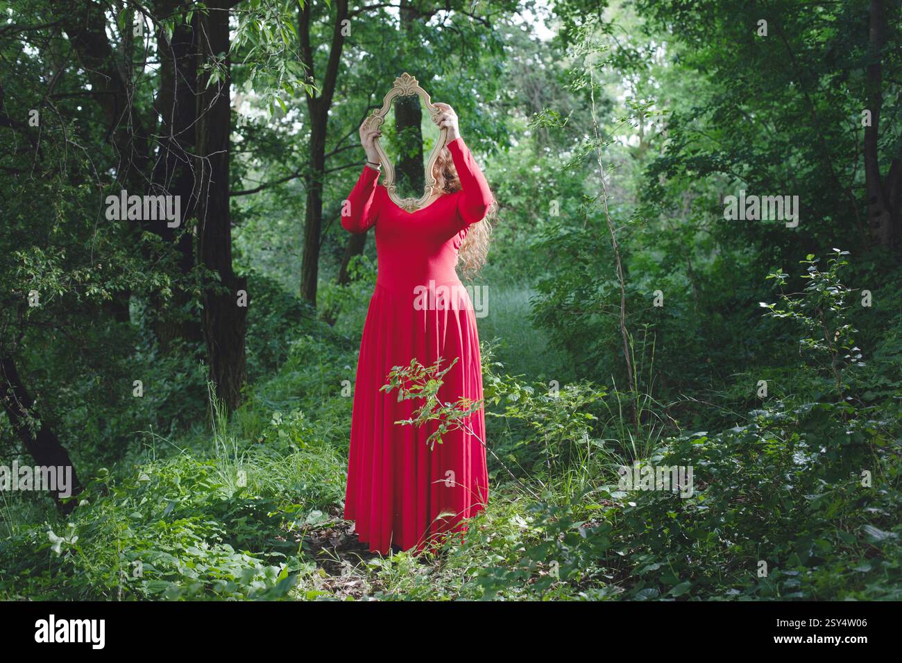 woman in red dress with mirror in front of her face reflecting the ...