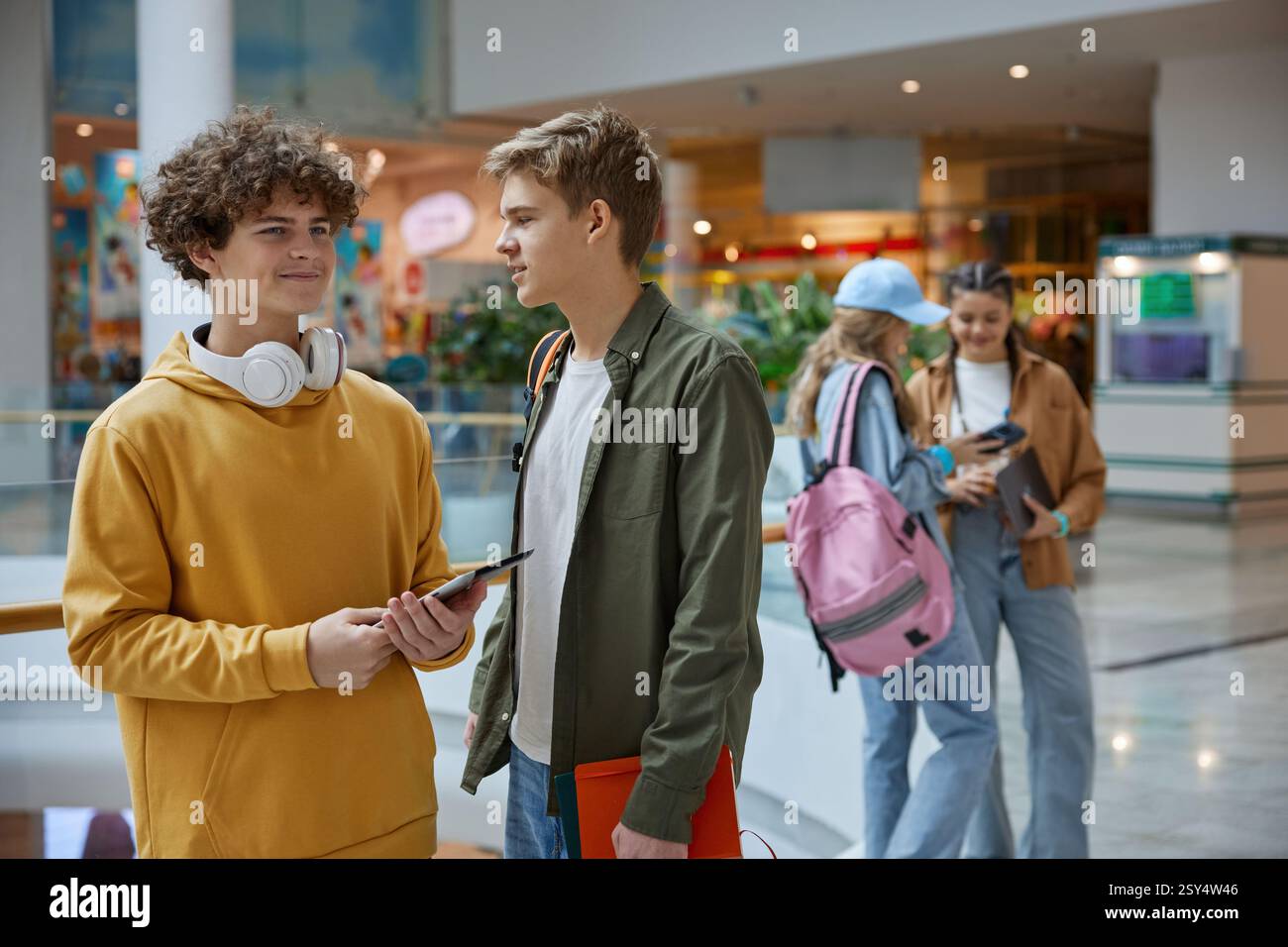 Happy teenagers walking through shopping mall hall Stock Photo - Alamy