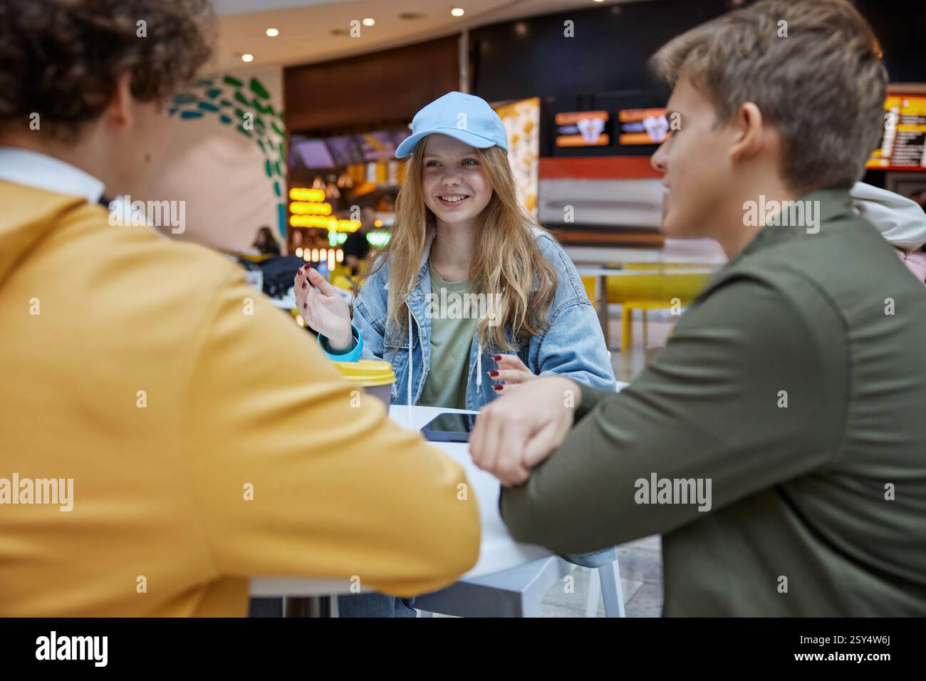 Teenage friends having fun while eating and drinking at food court of ...