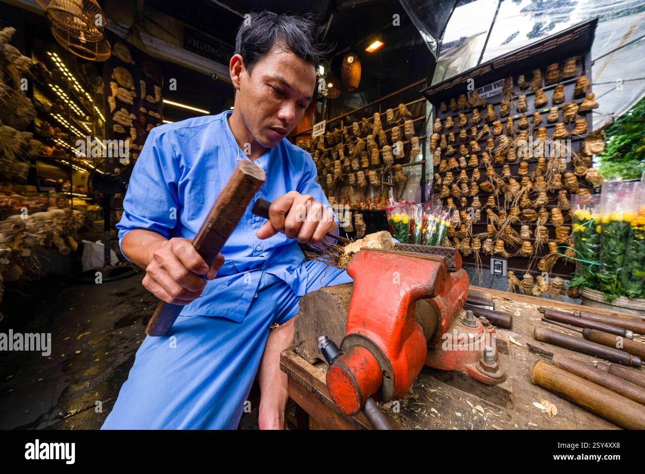 An artist carves small heads out of bamboo wood with roots on a ...