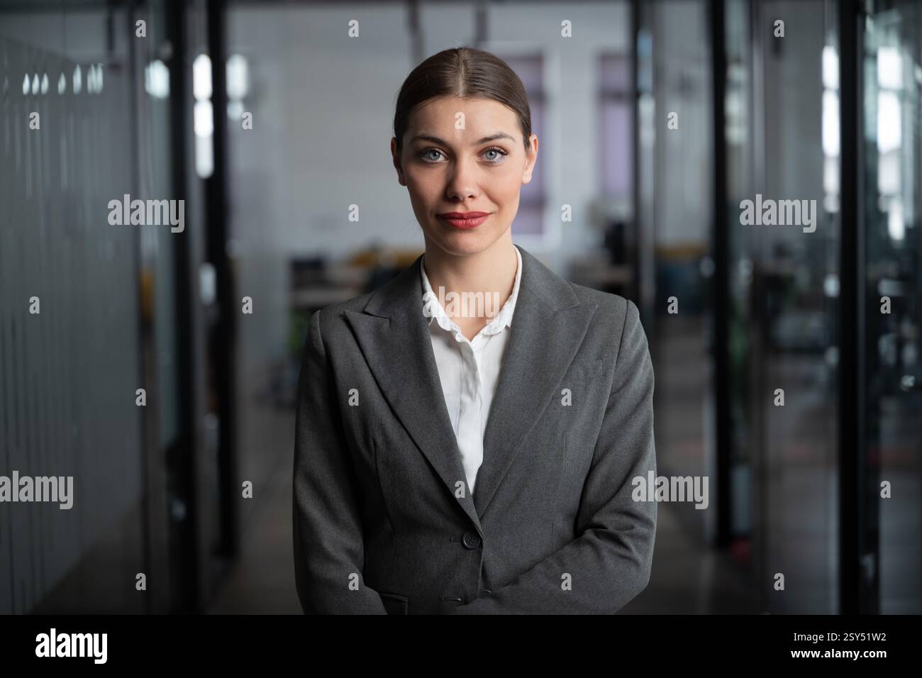 Professional businesswoman in a formal gray suit standing confidently ...