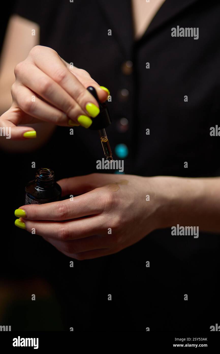 A close-up scene of female hands applying serum with a pipette for ...