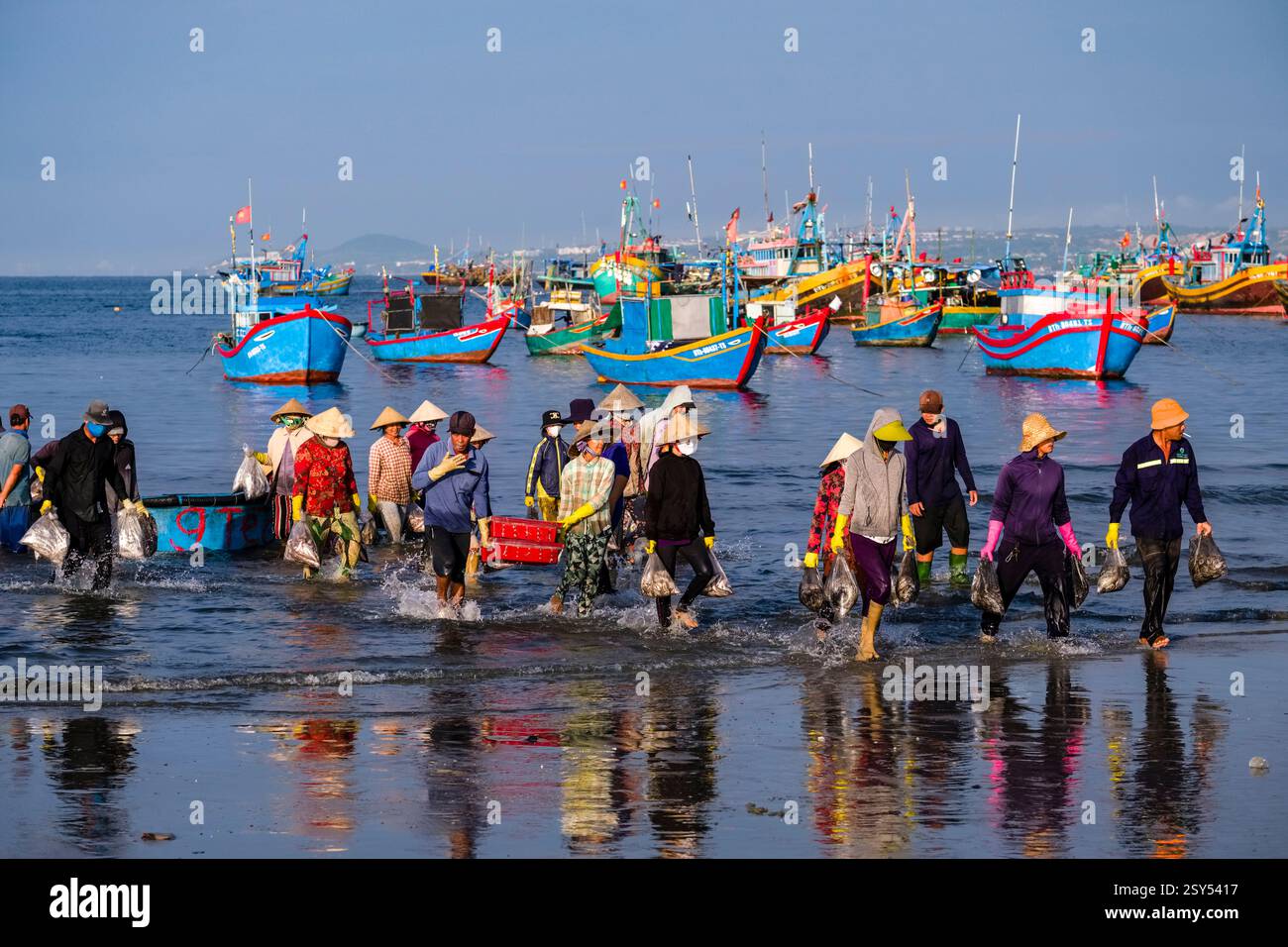 People carrying freshly caught fish in baskets to the beach at Mui Ne ...