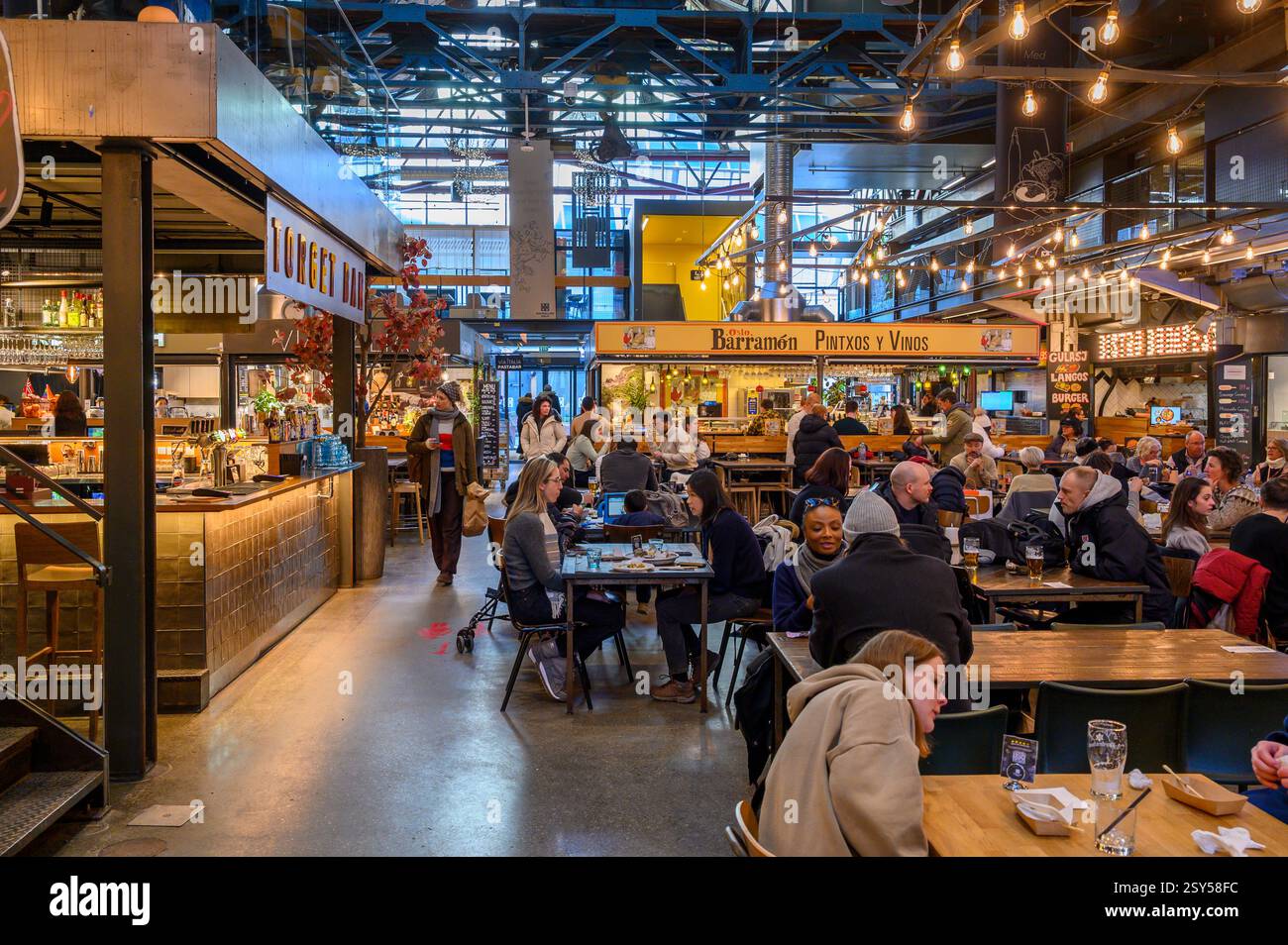 Inside Mathallen Oslo, an old industrial building converted to a food market with small ...