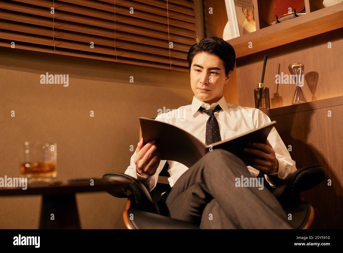 Japanese Man Sitting On A Chair Reading A Book Stock Photo - Alamy