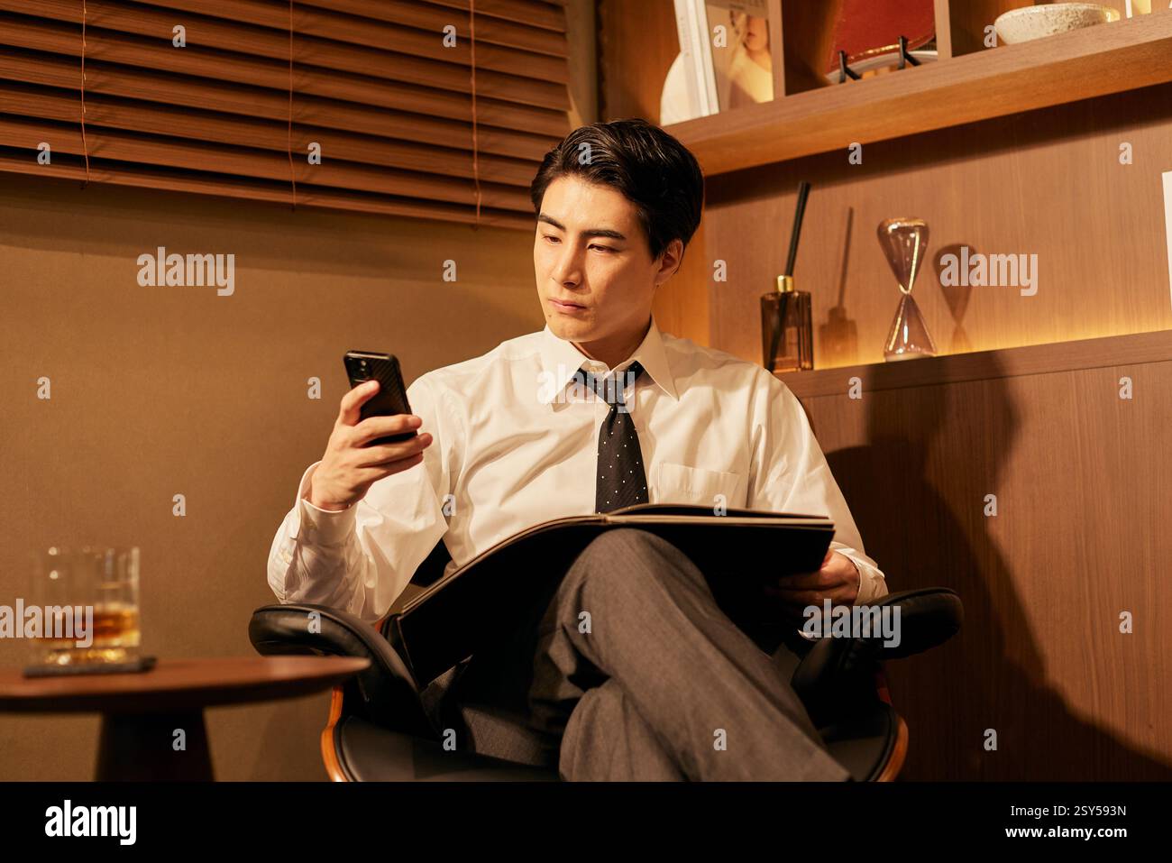 Japanese Man Sitting On A Chair Looking At Phone Stock Photo - Alamy