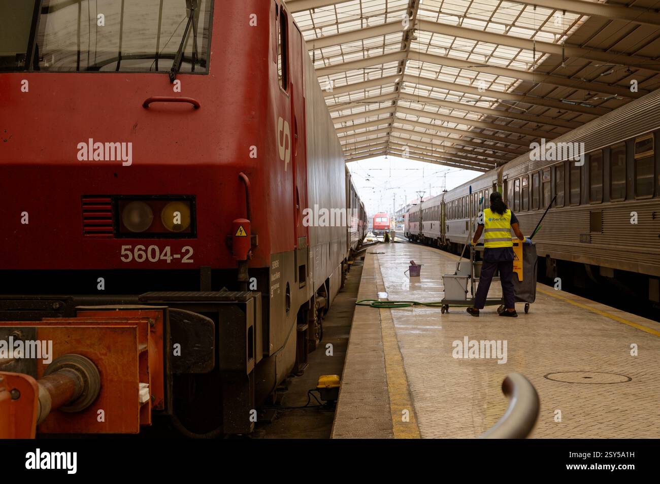 A railway worker cleans the platform at Santa Apolónia Station, with CP ...