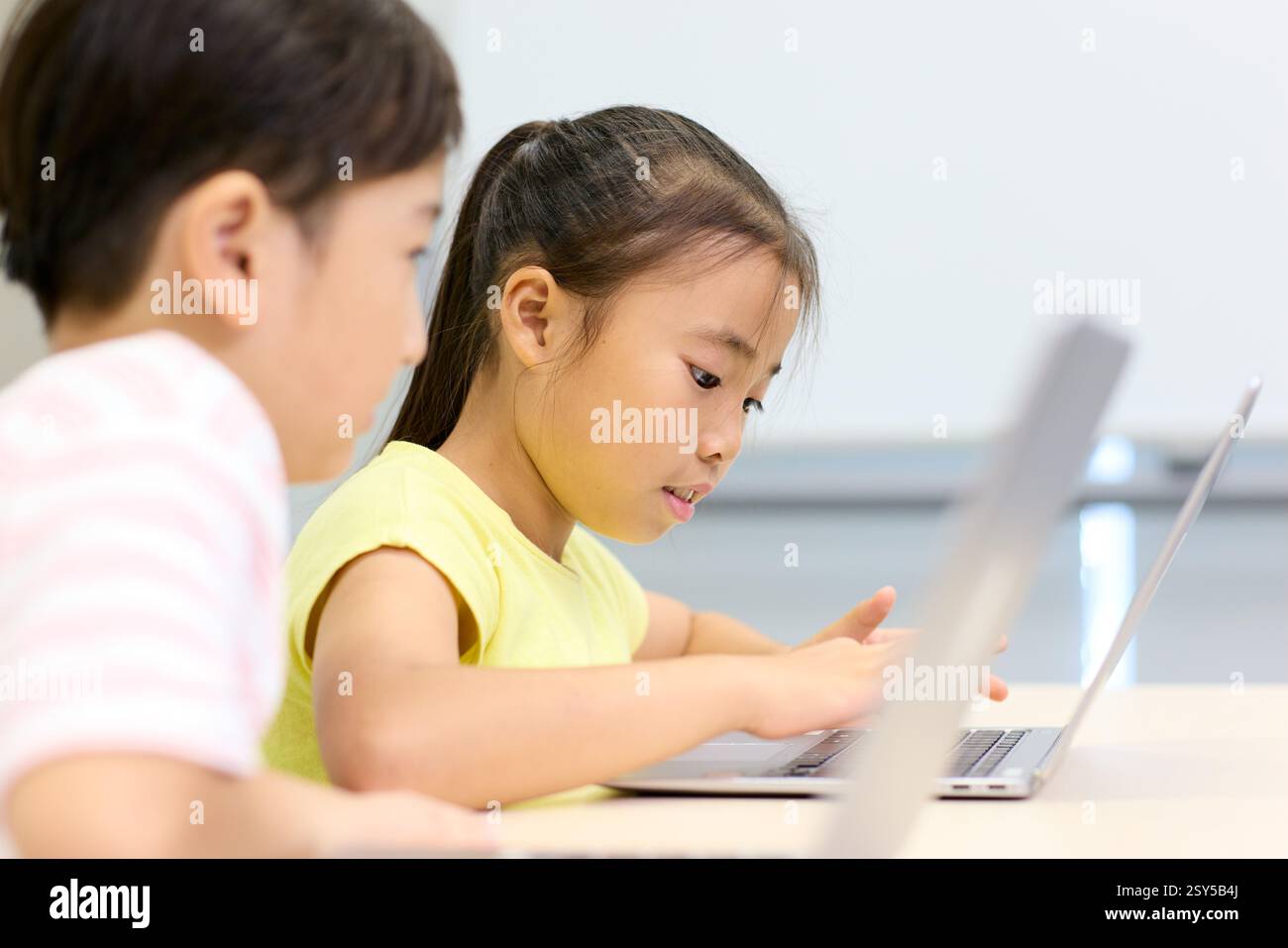 Two Children Using Laptops In A Classroom Stock Photo - Alamy
