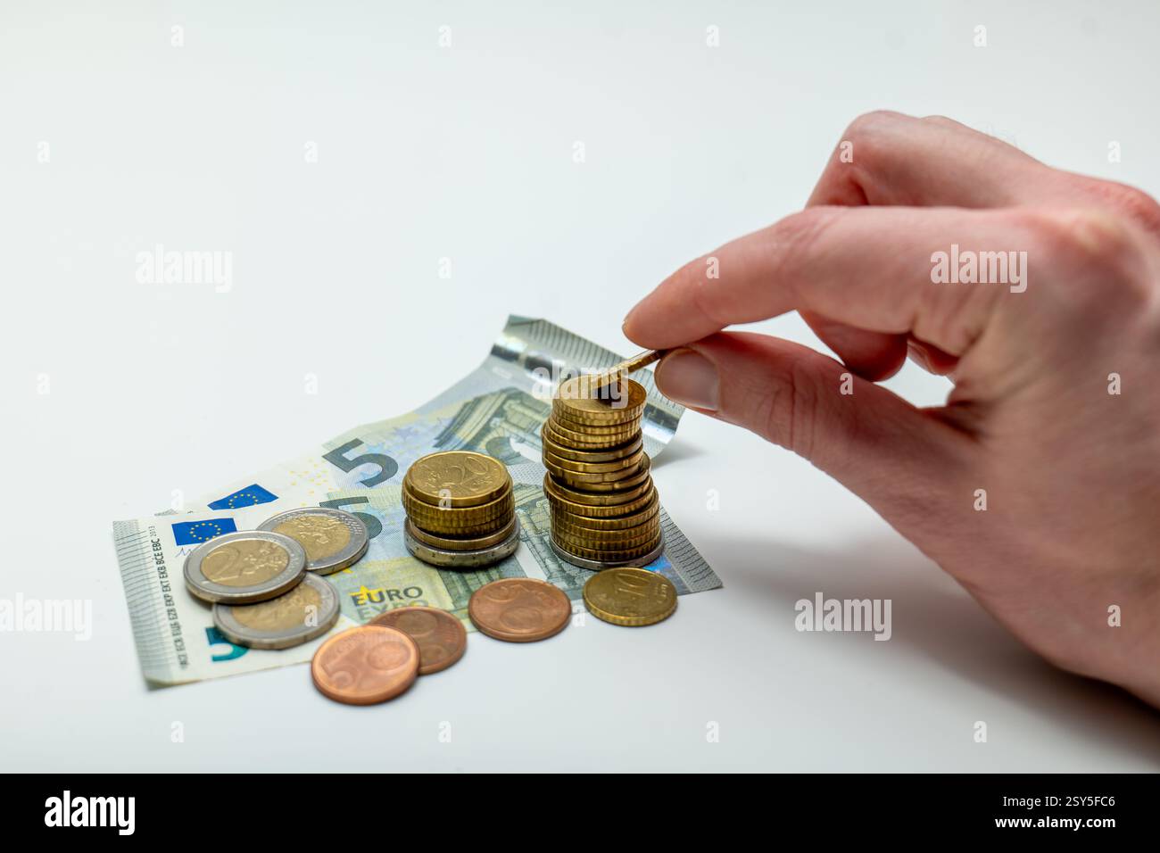 Hand calculating coins. 5 euro banknotes and coins isolated on white ...