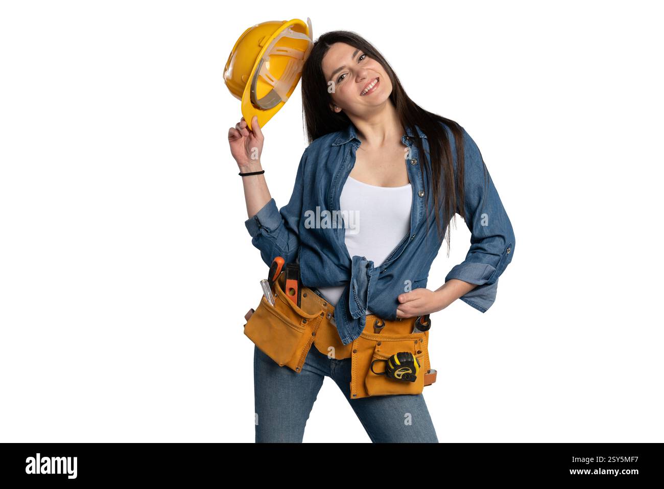 A happy female construction worker wearing a denim shirt, white tank top, and tool belt ...