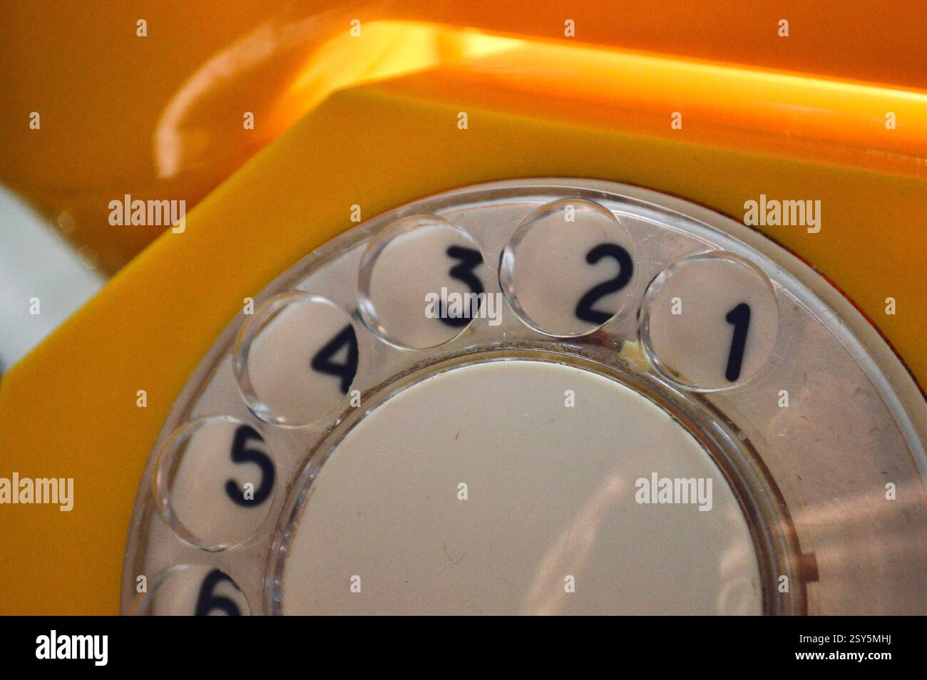 A vibrant yellow rotary telephone displays its vintage charm with a ...