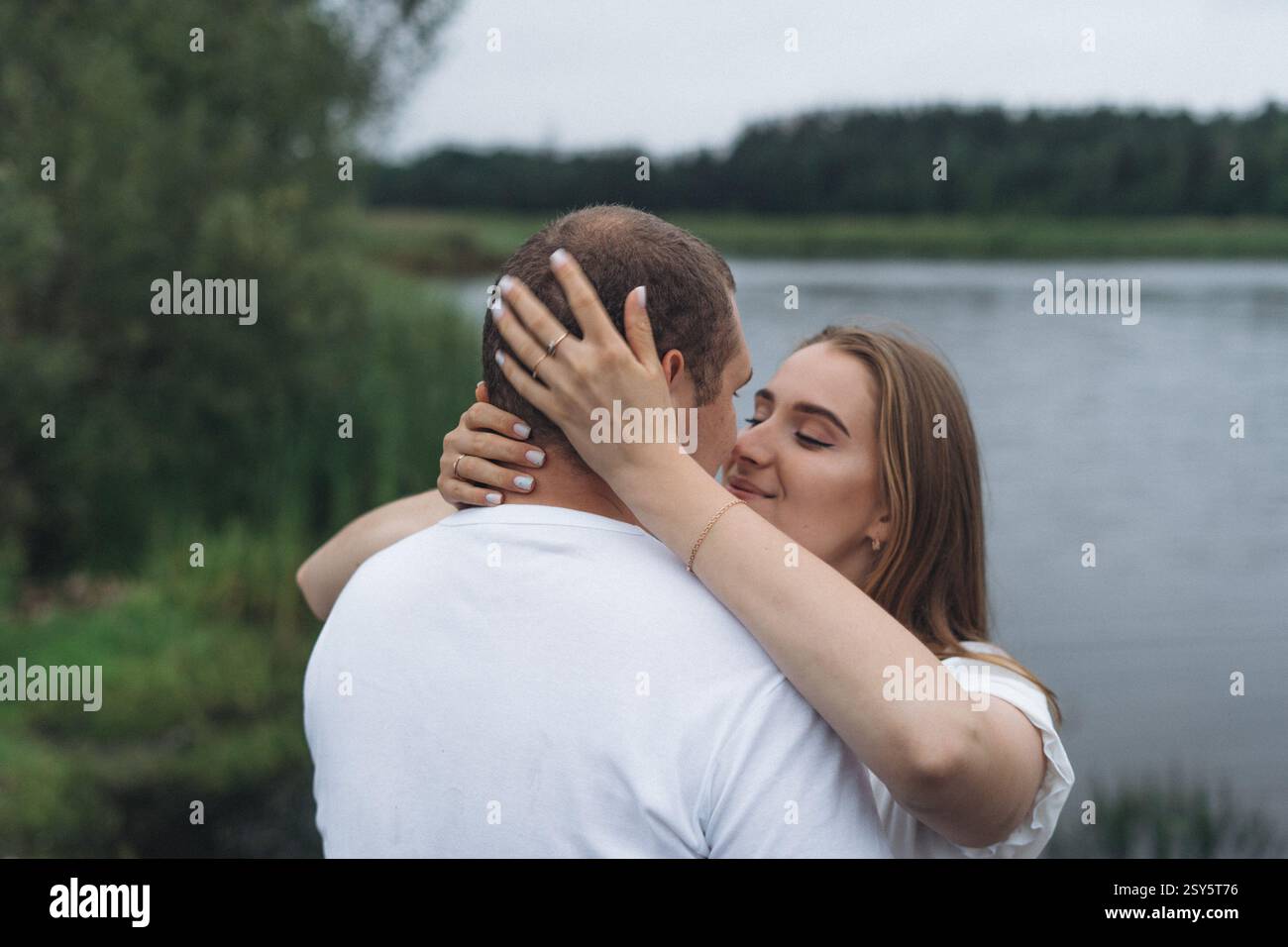 Romantic couple kissing and embracing near a lake and forest on a ...