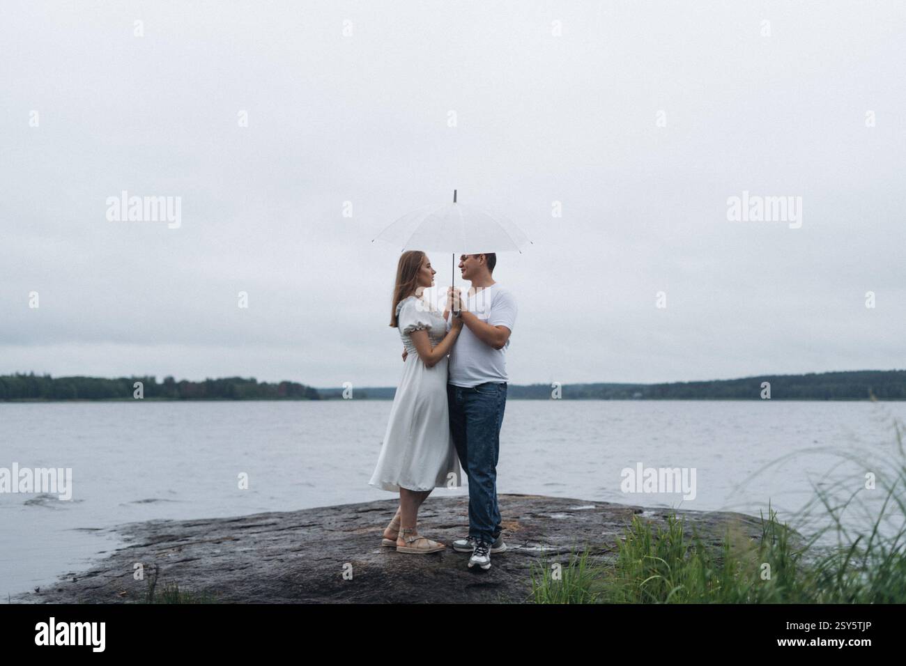 Romantic couple kissing and embracing near a lake and forest on a ...