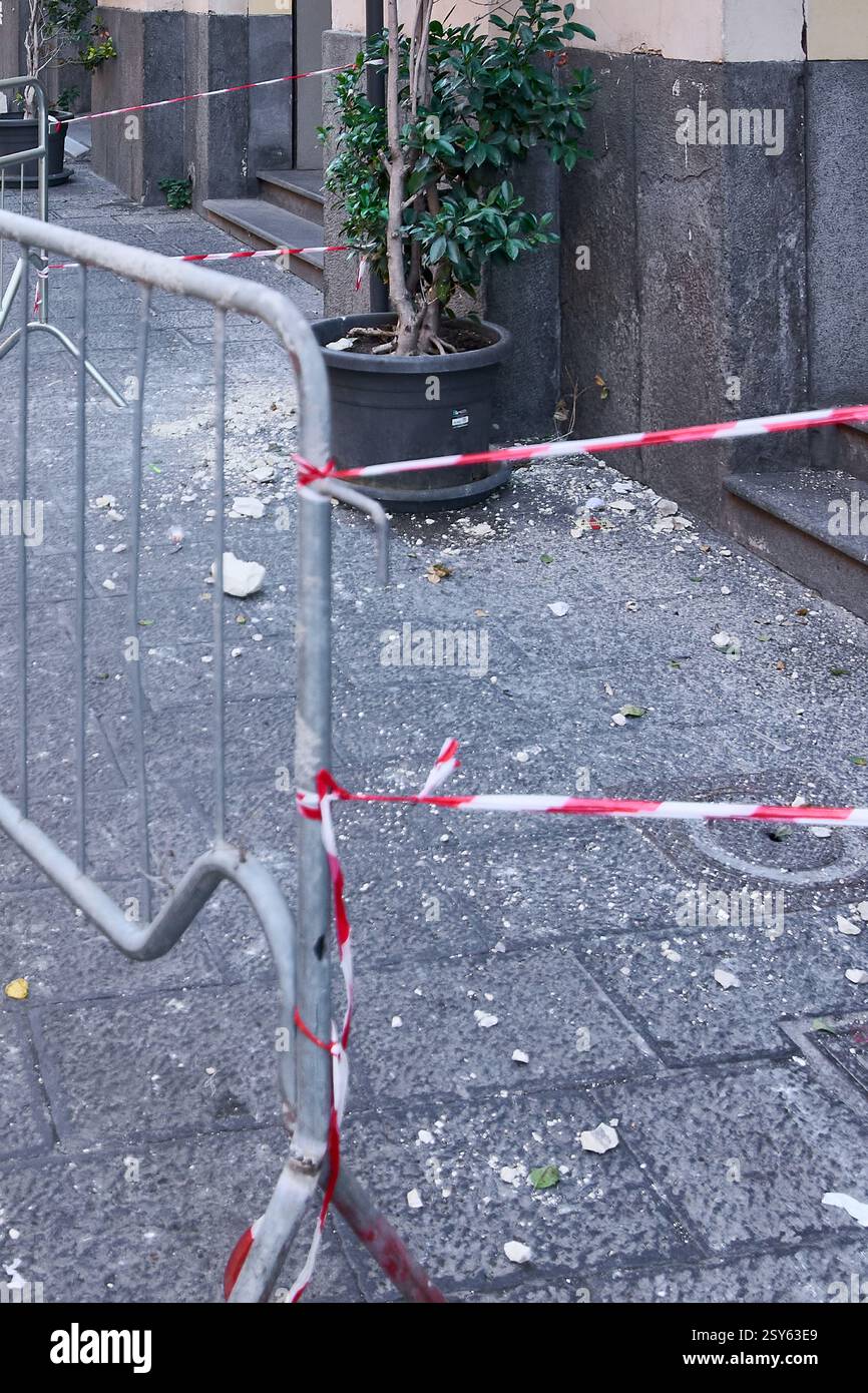 A facade collapse leaves debris strewn across a city sidewalk, marked ...