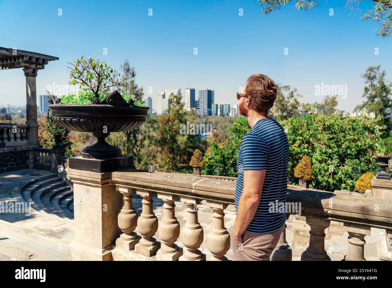 A tourist man standing at a terrace overlooking the Chapultepec Forrest ...