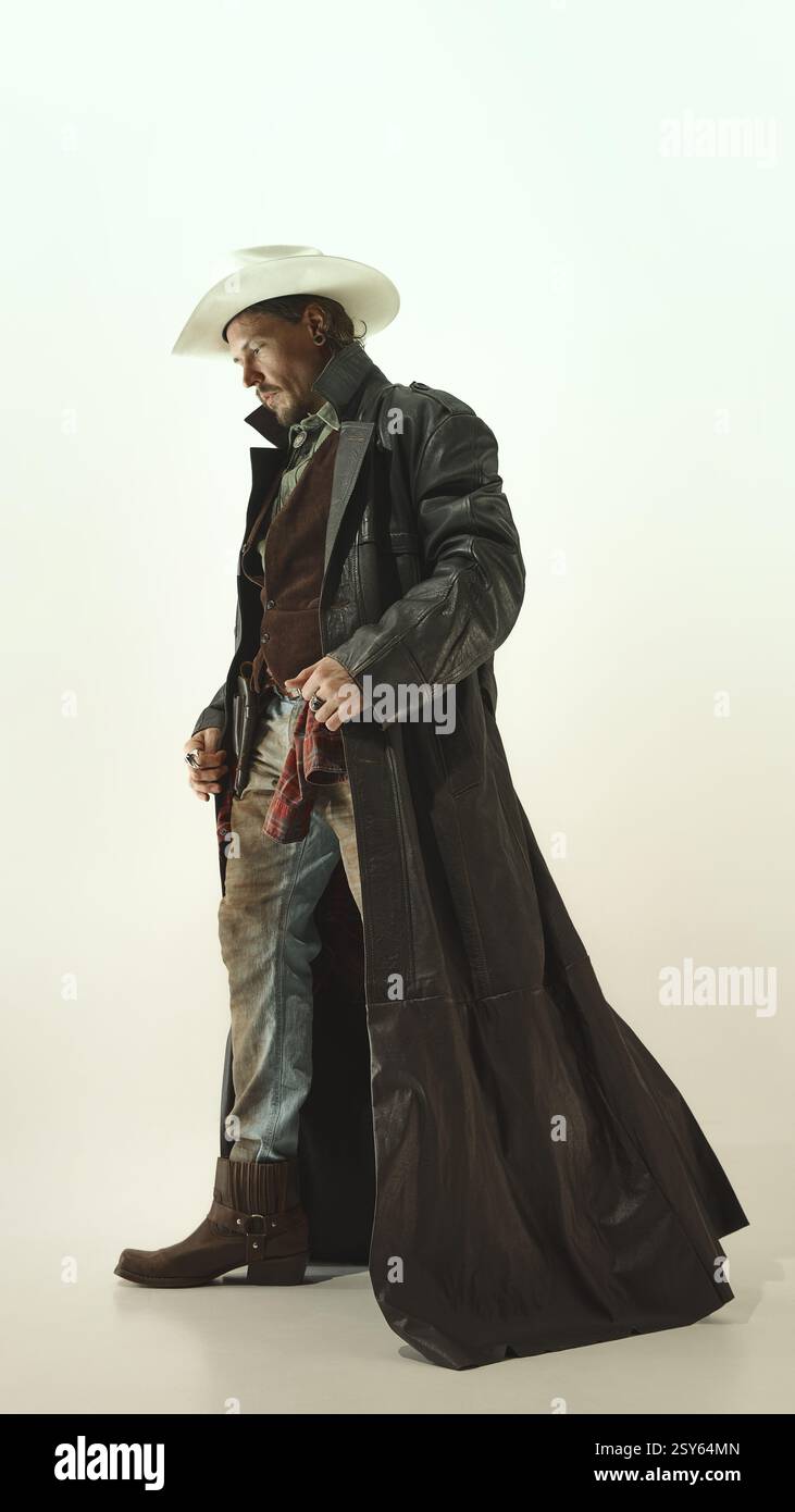 Side view full-length image of serious man, cowboy in leather trench ...