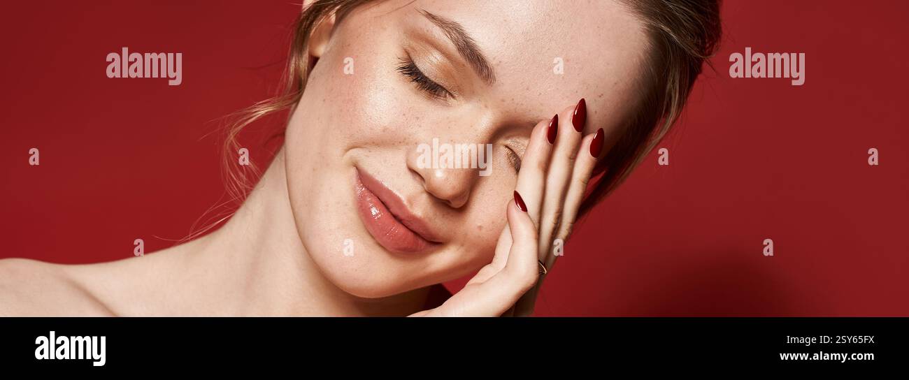 A young beautiful woman smiles softly while posing with one hand near ...