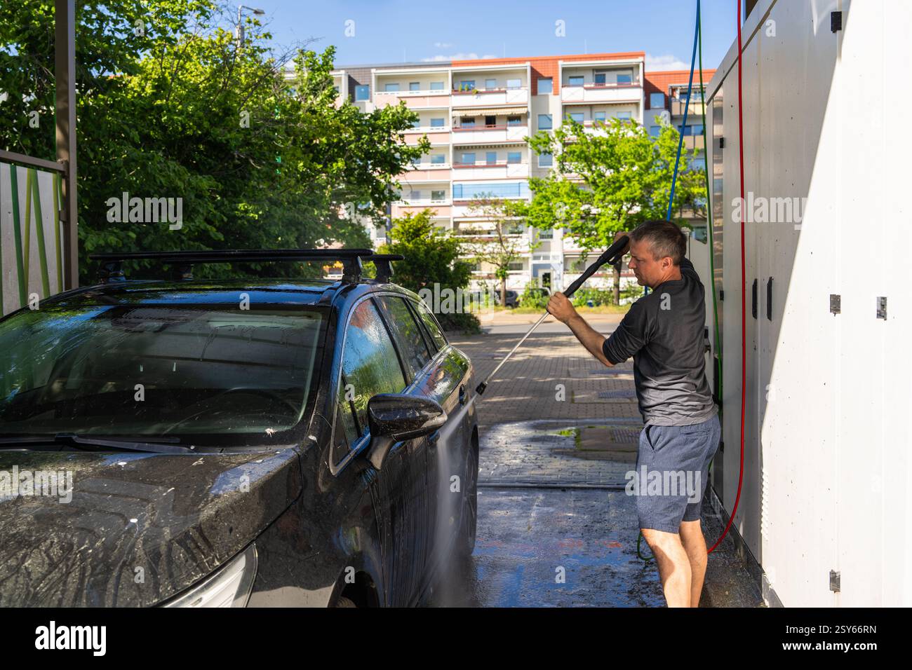 Man washes his car with water and soap at self-service car wash. Focus ...