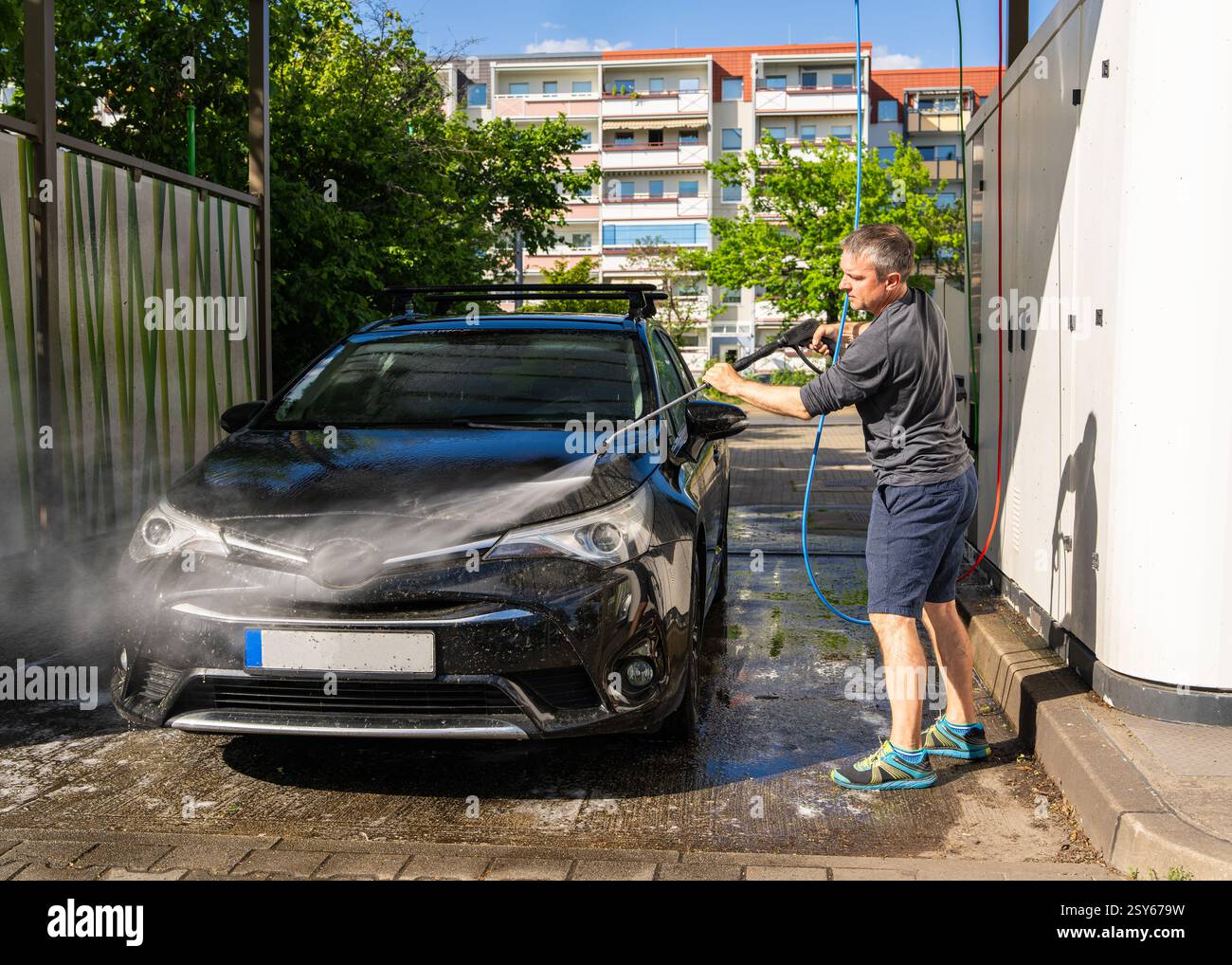 Man washes his car with water and soap at self-service car wash. Focus ...
