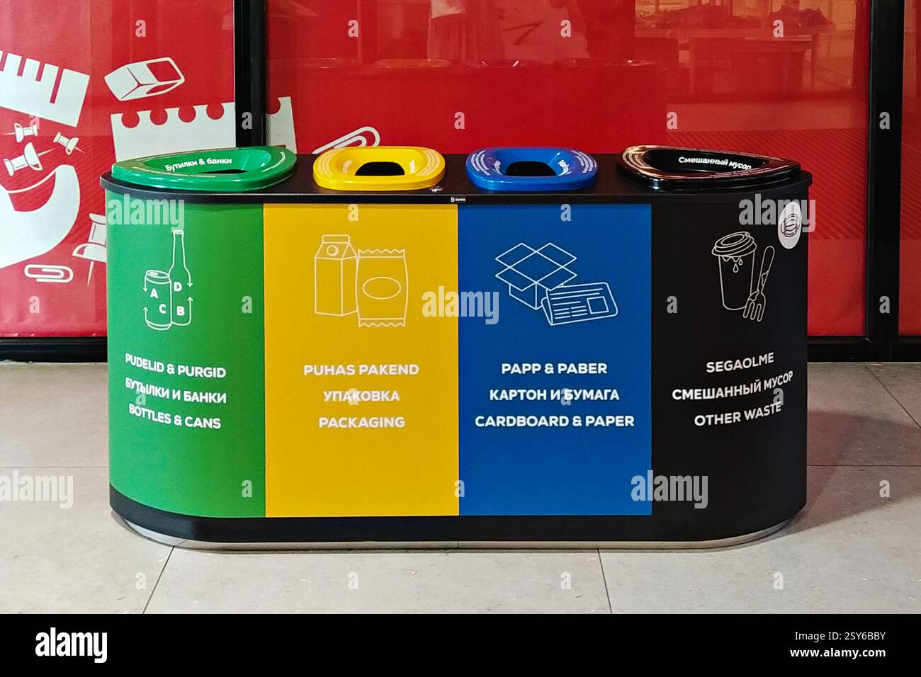 Set of four color-coded recycling bins labeled for bottles, packaging ...