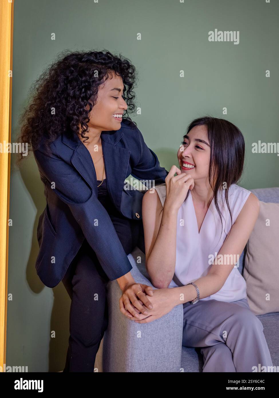 Two lgbtq confident, diverse women embracing and smiling in a moment of supportive friendship ...